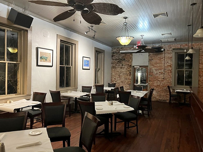 Exposed brick walls meet white tablecloths in a dining room that feels like the living room of that friend who somehow always cooks better than everyone else.