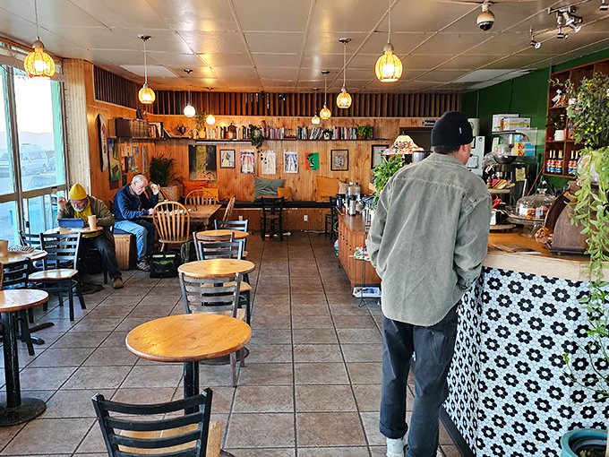Cozy wood-paneled interior with hanging pendant lights creates the perfect backdrop for both serious coffee drinking and contemplative ocean gazing.