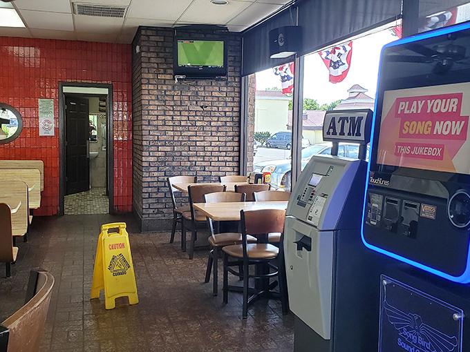 Classic diner ambiance with brick walls, simple seating, and that essential jukebox. The "Play Your Song Now" sign is practically daring you to choose something from the 70s.
