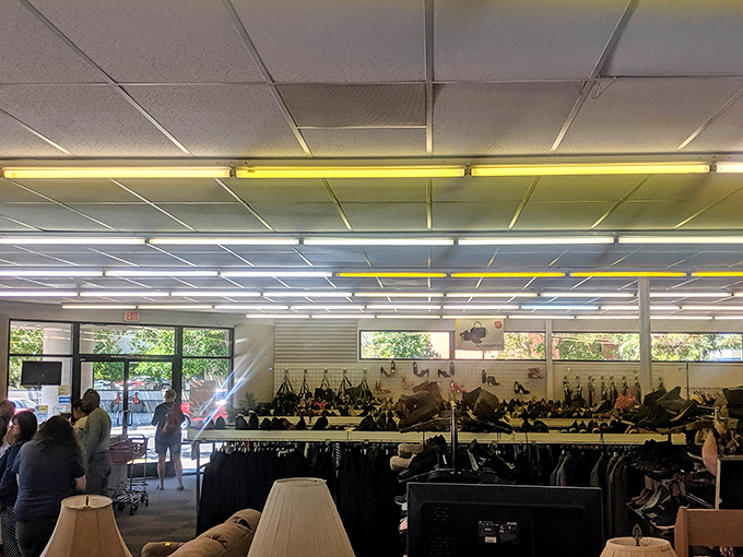 Fluorescent lights illuminate the promised land of pre-loved treasures, where shoppers navigate racks with the focus of archaeologists on a career-defining dig.