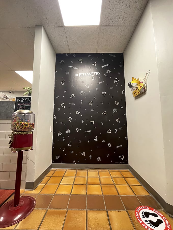 A pizza-patterned accent wall and vintage gumball machine create that perfect "neighborhood joint" atmosphere. The social media hashtag shows they're traditional yet current.