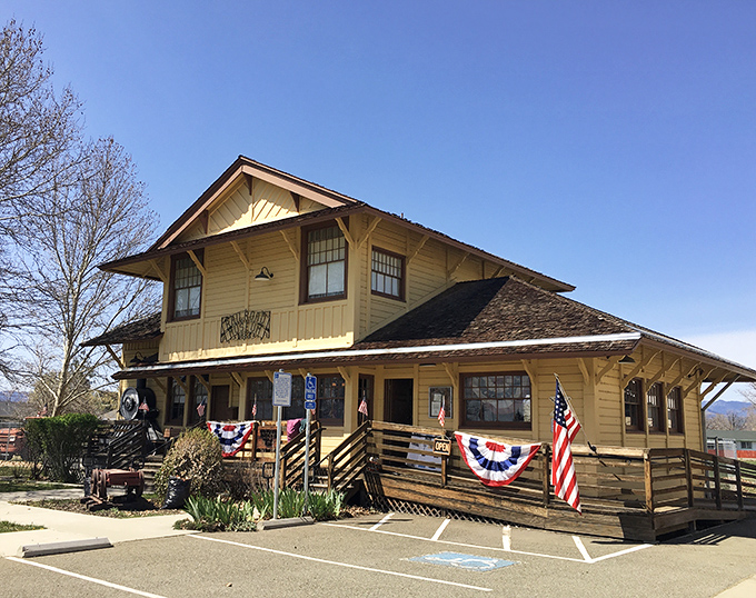The historic yellow train depot stands as proudly as a grandfather showing off family photos, preserving Montague's railroad heritage with patriotic flair.