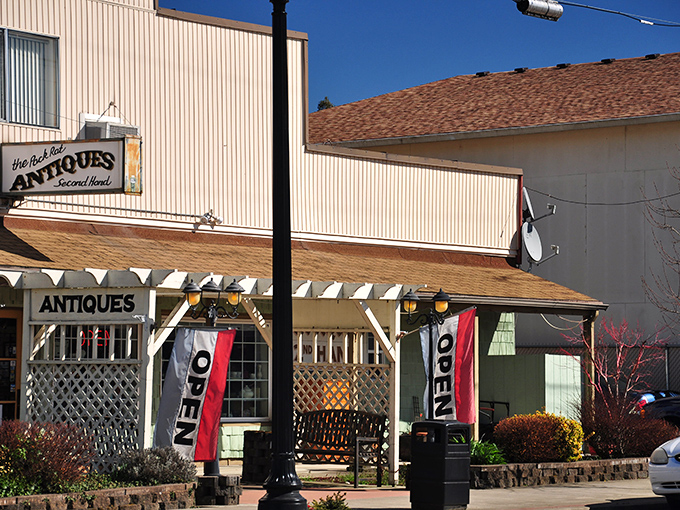 The Pack Rat Antiques welcomes treasure hunters with its inviting porch and fluttering "OPEN" flags &ndash; your first clue that discoveries await inside.