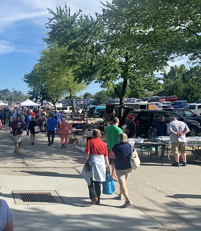 Weekend warriors on the hunt. Shoppers navigate the outdoor vendor area under shady trees, tote bags already filling with found treasures.