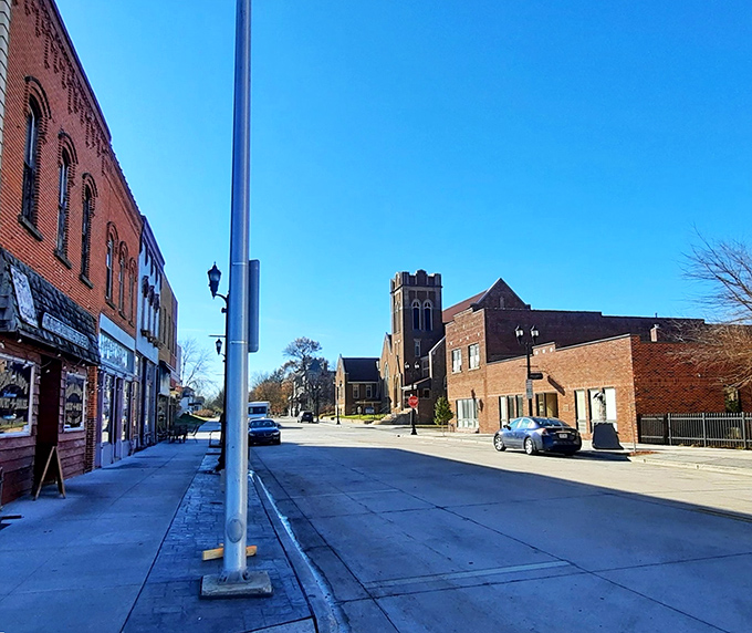 Small-town charm meets architectural character on this quiet Eau Claire street, where brick buildings whisper stories of the past under impossibly blue Midwestern skies.