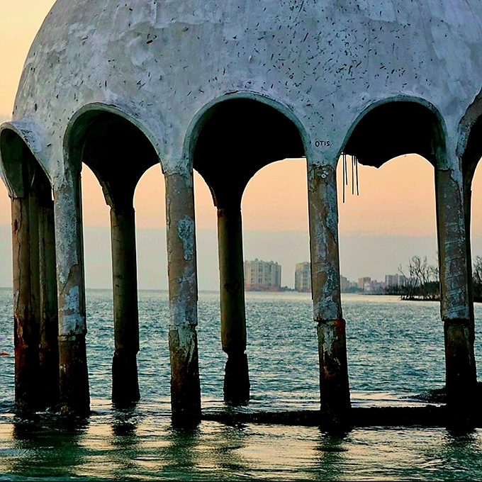 The dome's concrete arches stand as silent sentinels to coastal change, their elegant curves catching golden hour light like nature's amphitheater.
