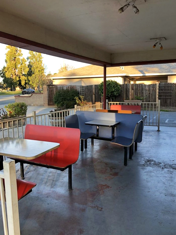 Red and blue bench seating under a simple awning&mdash;where conversations flow as freely as the ketchup and nostalgia comes standard with every meal.