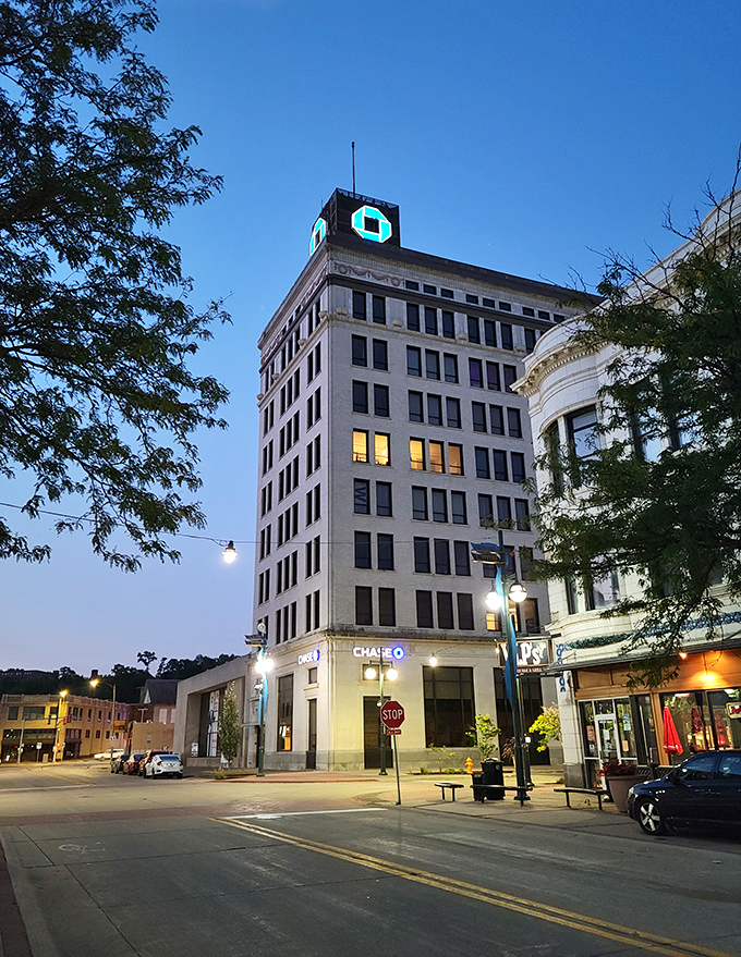 As twilight descends, Moline's skyline glows with quiet dignity, the illuminated office building standing sentinel over streets that once echoed with industrial might.