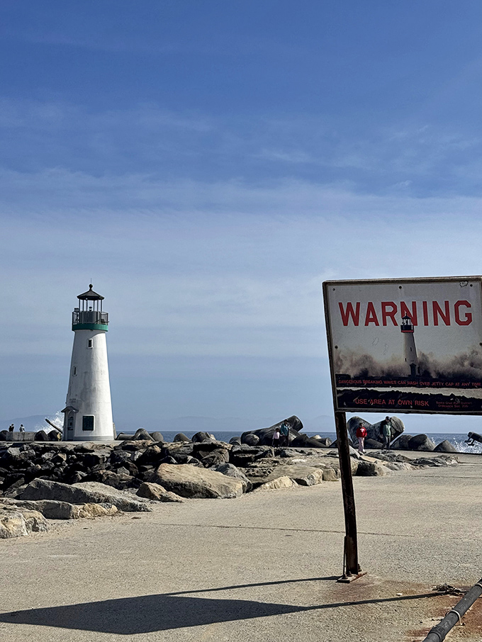 Nature's warning system: The sign reminds visitors that the sea demands respect, while the lighthouse offers a beacon of reassurance in the background. 