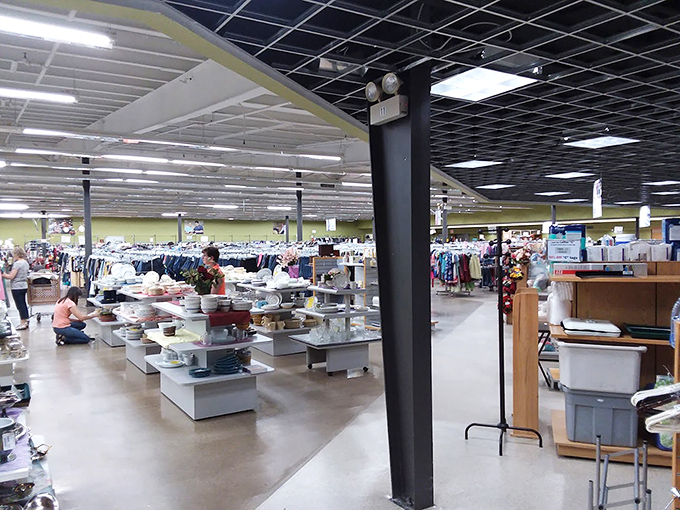 A thrifter's paradise unfolds under the black grid ceiling, where rows of housewares and clothing create a wonderland of possibilities.