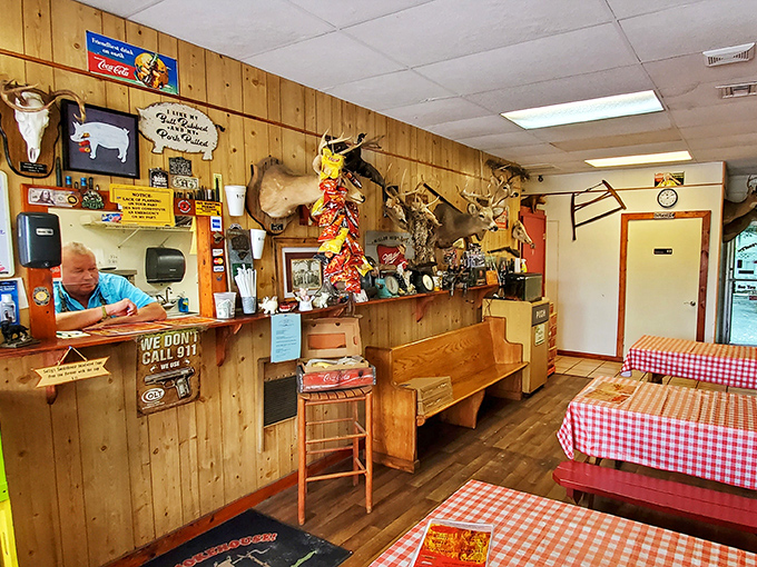 Wood-paneled walls adorned with hunting trophies create the perfect rustic backdrop for serious barbecue consumption. The "We Don't Call 911" sign says it all.