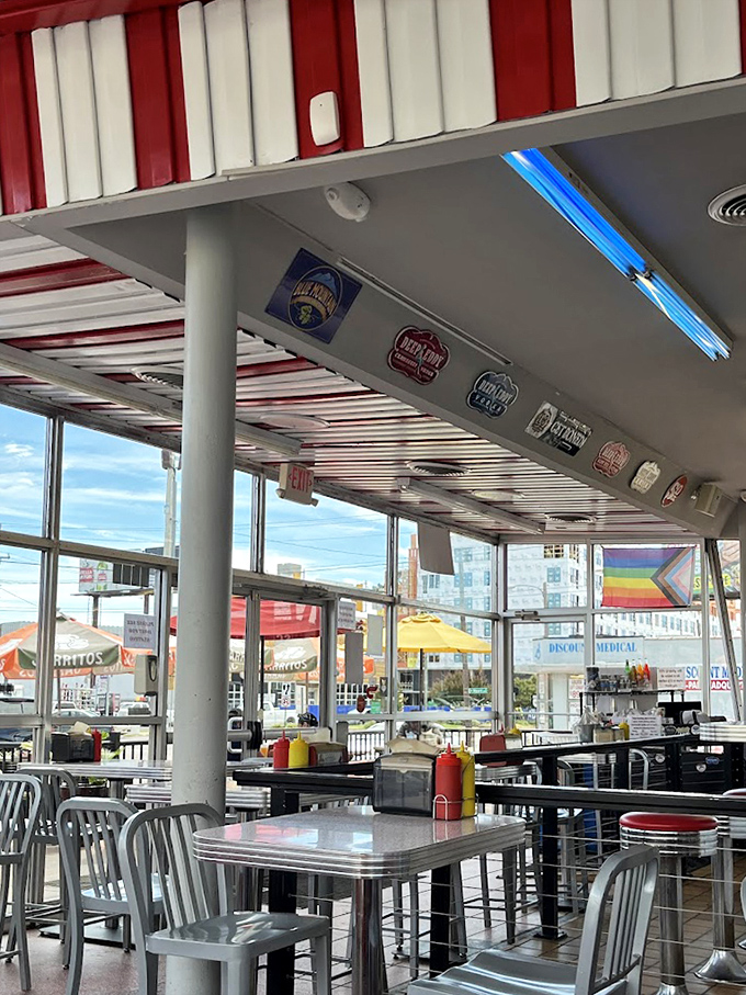 Classic Americana with a modern twist—red and white stripes overhead, beer signs aplenty, and those unmistakable diner-style metal chairs.
