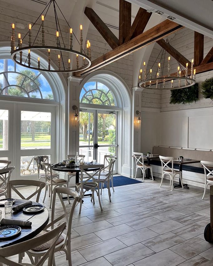Soaring arched windows flood the dining room with Florida sunshine, while those circular chandeliers cast the kind of glow that makes everyone look like they're on vacation.