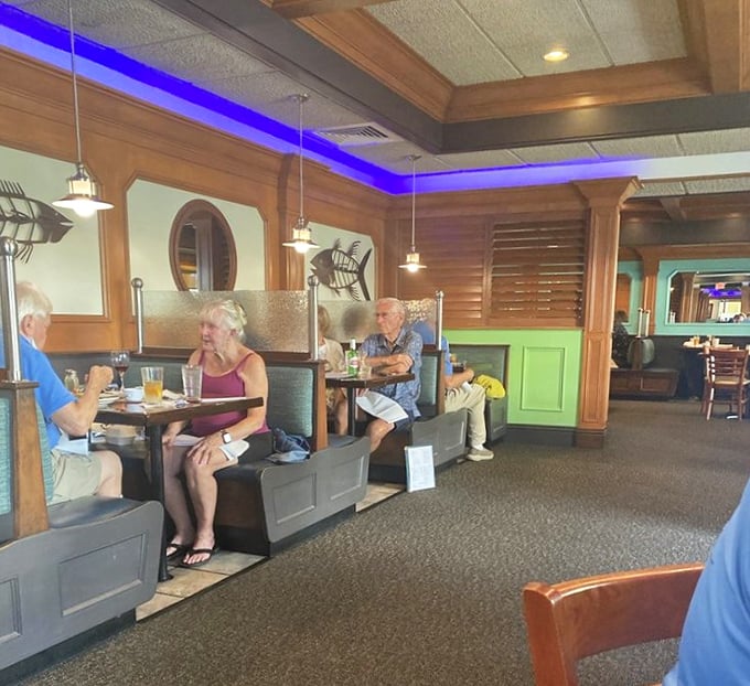 Blue lighting transforms this dining room into an underwater fantasy. The wooden accents and fish decor say "yes, we're serious about seafood" without shouting it.