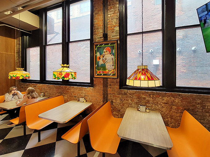 Orange booths pop against exposed brick walls while Tiffany-style lamps cast a warm glow—pizza parlor design perfected with a dash of Cleveland cool.