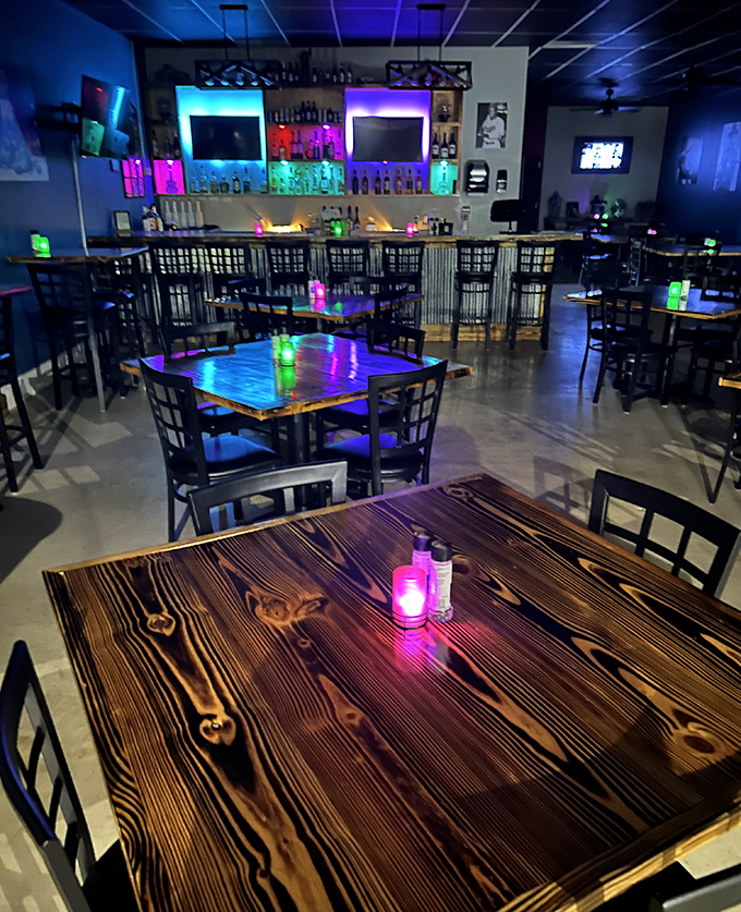 Step inside and the mood shifts dramatically—rustic wooden tables bathed in electric blue and purple light create an atmosphere that's both modern and inviting.