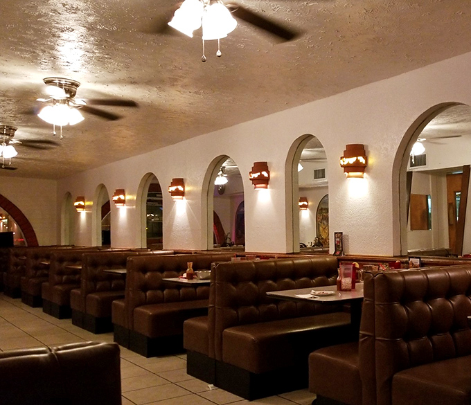 Step inside to discover a warm, inviting space where arched doorways create cozy dining nooks. The comfortable leather booths practically whisper, "Stay awhile, amigo."