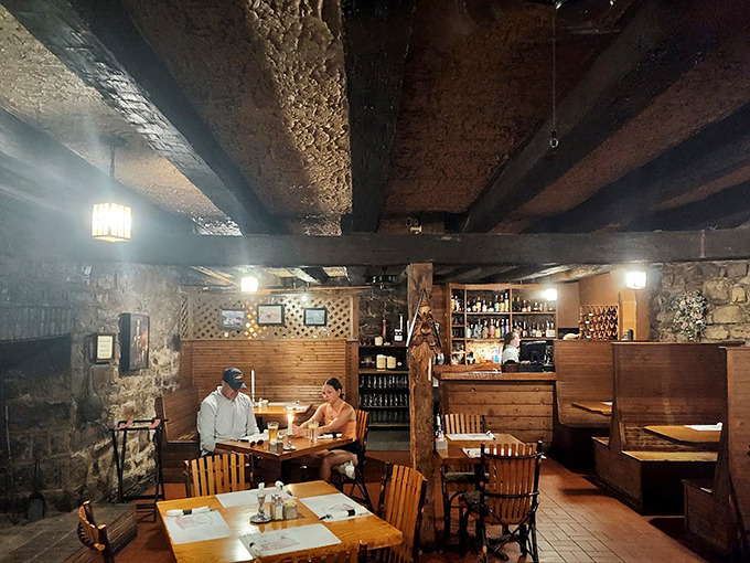Centuries-old beams hover overhead like silent witnesses to countless conversations, while stone walls cradle modern diners in historical embrace.