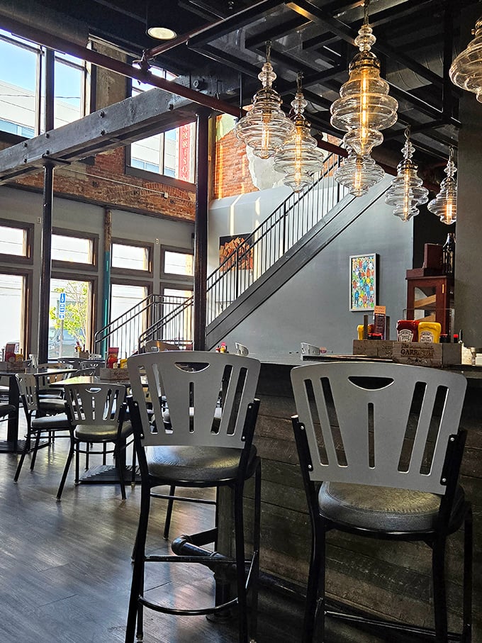 Industrial chic meets small-town charm with soaring ceilings, glass pendant lights, and a staircase that invites you to explore both levels of flavor.