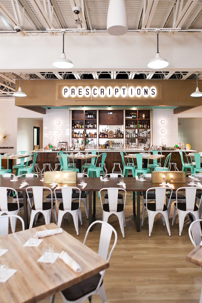 The "PRESCRIPTIONS" sign above the bar suggests the only medicine you need might be their signature biscuits and a strong mimosa.