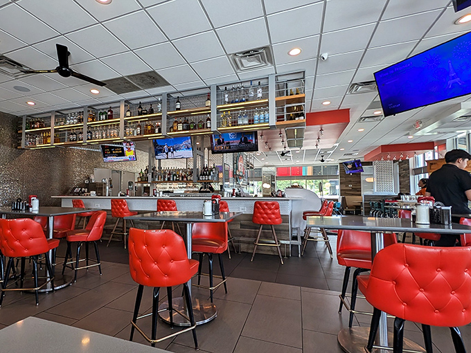 Red tufted chairs pop against the modern interior, creating a diner atmosphere that's less "greasy spoon" and more "polished silver."