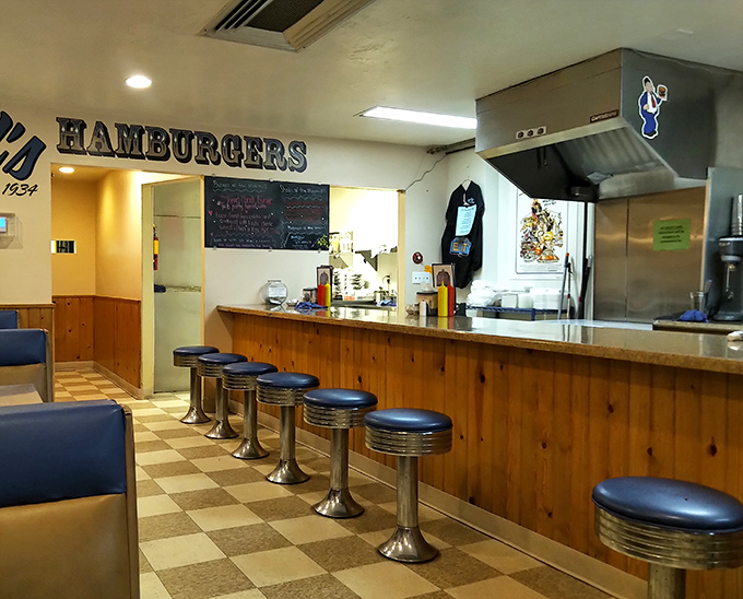 Classic chrome stools and a checkerboard floor set the stage for burger theater—this isn't retro by design, it's authentic by survival.