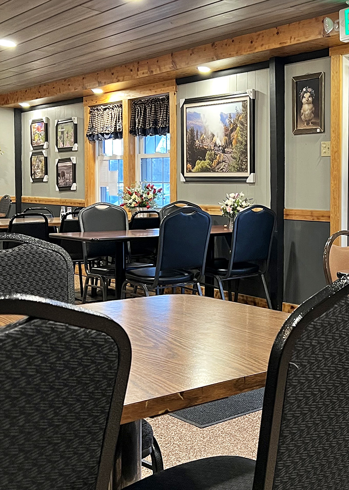 A cozy dining room with neatly arranged tables and chairs, decorated with charming artwork and fresh flowers, inviting guests to relax and enjoy a warm meal.