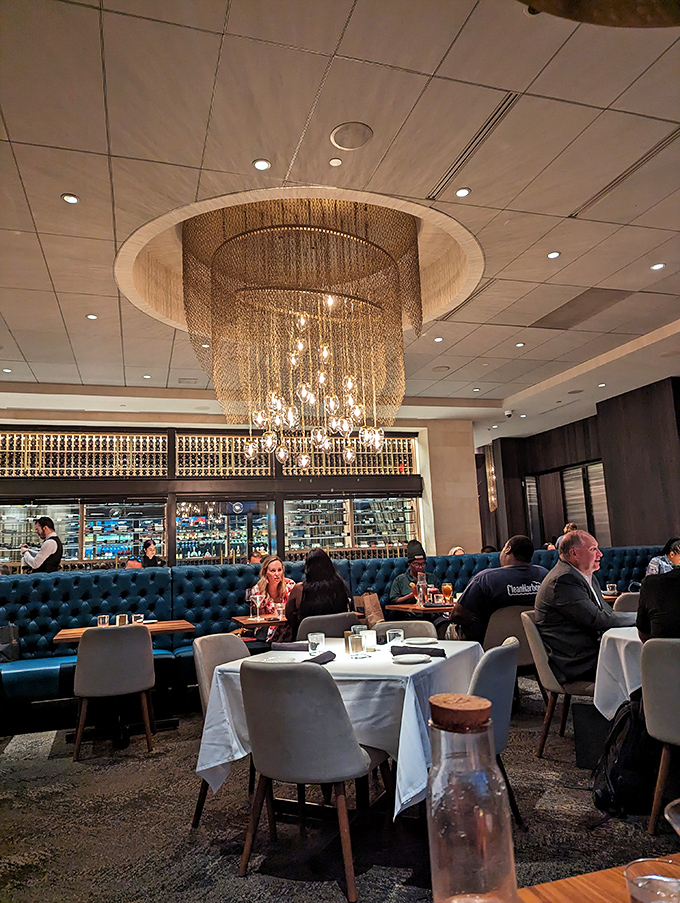 That chandelier isn't compensating for anything&mdash;the food stands tall on its own. Elegant lighting, plush blue booths, and white tablecloths set the stage.
