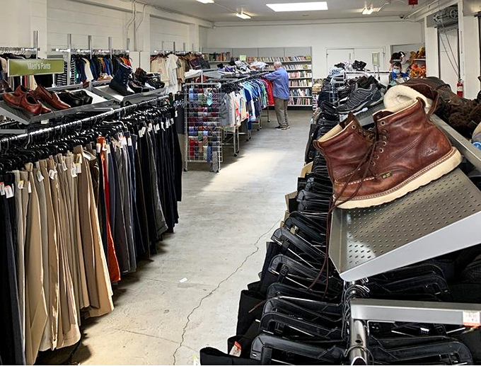 Organized chaos at its finest—racks of potential wardrobe upgrades await, with leather work boots standing at attention like soldiers guarding fashion finds.
