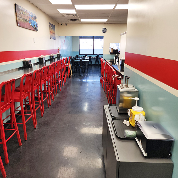Red stools lined up like eager patrons themselves, waiting for the lunch rush in a space where nostalgia meets modern burger craftsmanship.