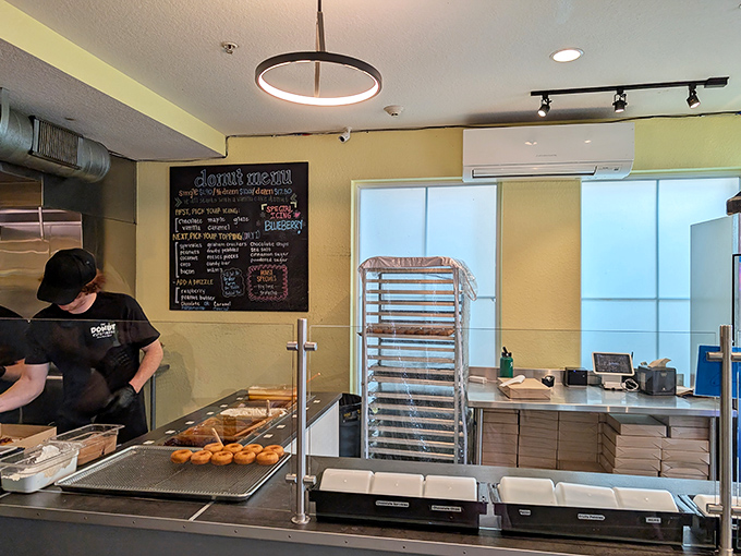 Behind the counter, culinary magic happens in real-time as fresh donuts emerge ready for their glow-up of toppings and drizzles.
