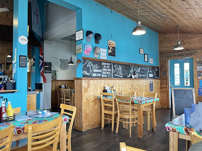 Bright blue walls meet warm wooden paneling in this cozy interior where every colorful oilcloth-covered table promises a memorable meal.