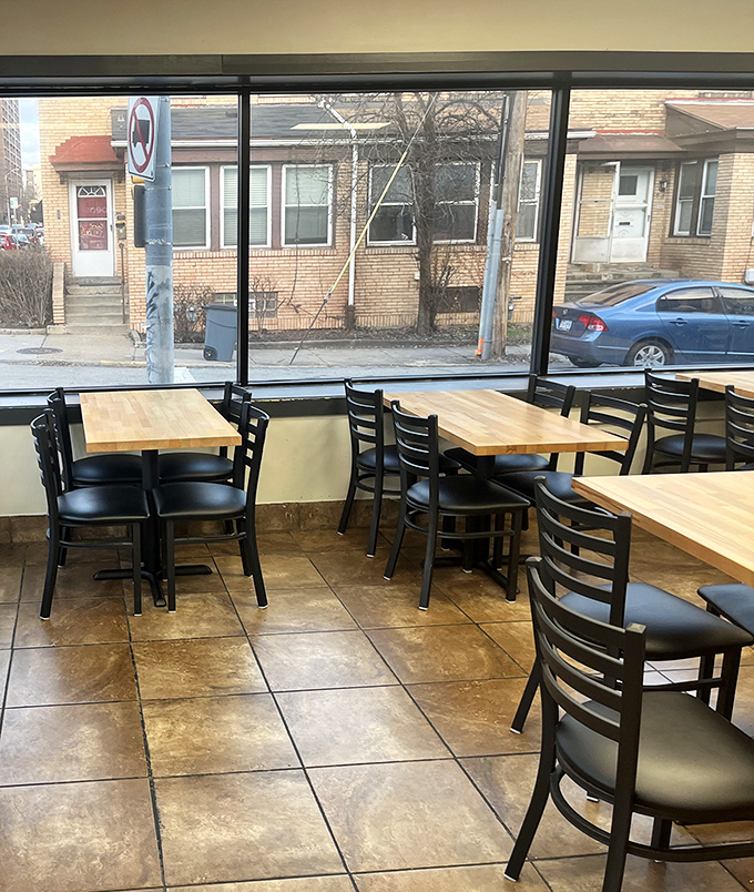 Simple wooden tables and black chairs create a no-nonsense dining space where the food, not the decor, rightfully takes center stage.