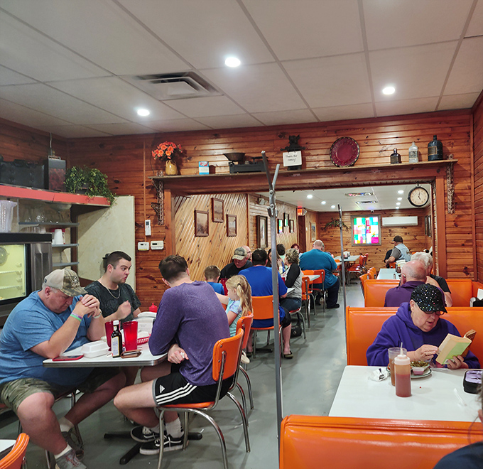 Inside, wood-paneled walls and bright orange booths create that perfect small-town atmosphere where conversations flow as freely as the coffee.