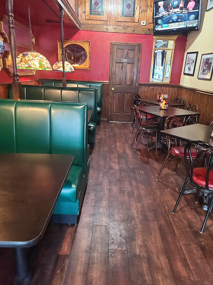 Inside, rich red walls meet classic wood paneling, while Tiffany-style lamps cast a warm glow over comfortable green booths.