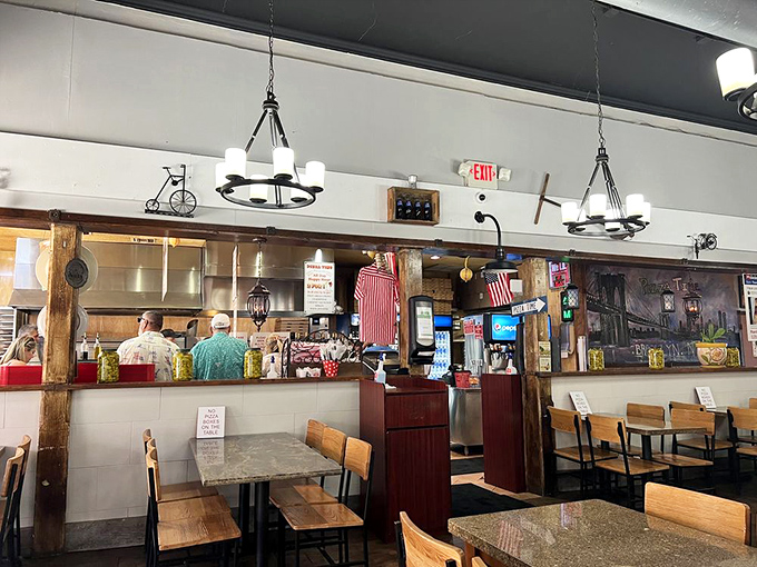 Simple wooden tables, no-nonsense chairs, and the open kitchen create that authentic pizzeria atmosphere where the focus remains squarely on what matters: the food.