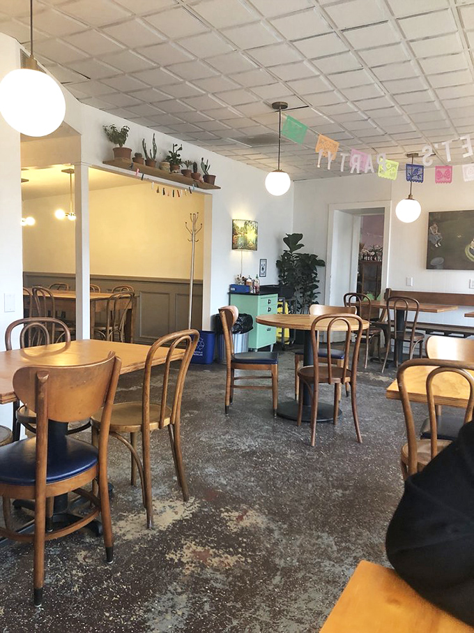 Vintage wooden chairs, potted plants, and colorful papel picado banners create that rare atmosphere where both hipsters and grandparents feel equally at home.