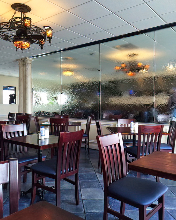 Textured glass dividers and warm wooden chairs create intimate dining spaces that transport you straight to Greece without the passport or jet lag.