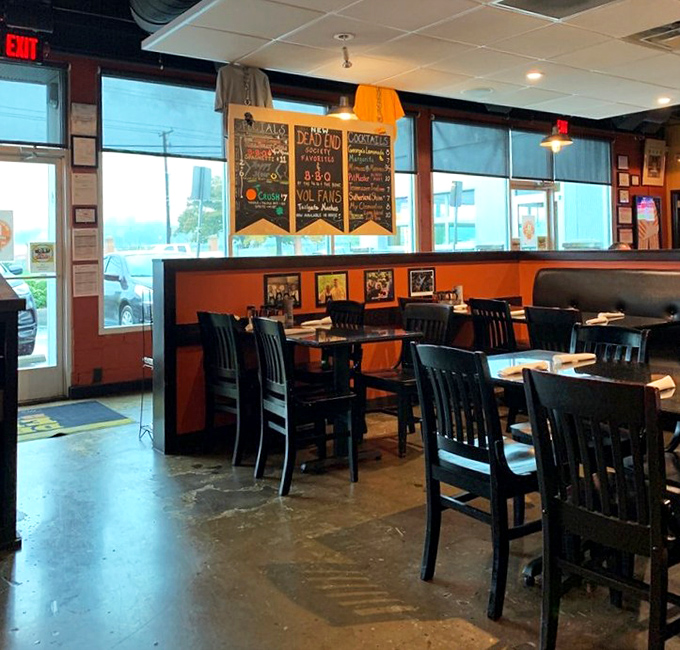Orange walls and black chairs create that perfect "come as you are" vibe where both business suits and work boots feel equally at home.