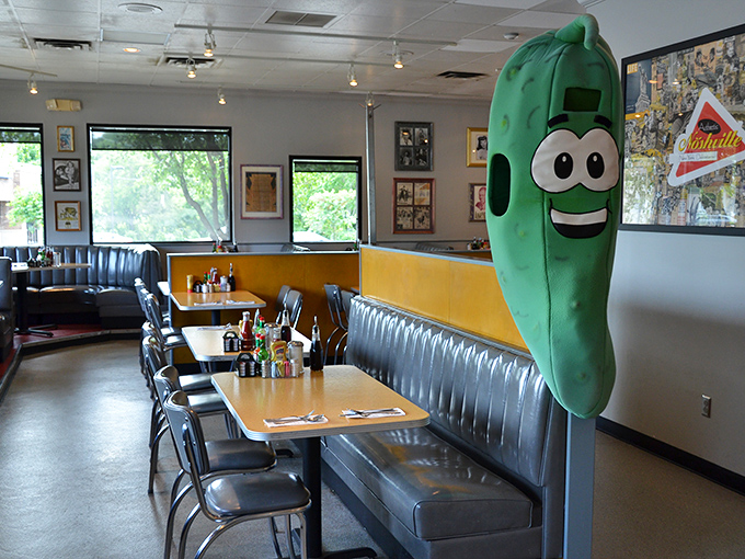 Meet the unofficial greeter of Noshville &ndash; a giant pickle mascot who never complains about standing all day. The classic diner booths behind him have witnessed countless food epiphanies.