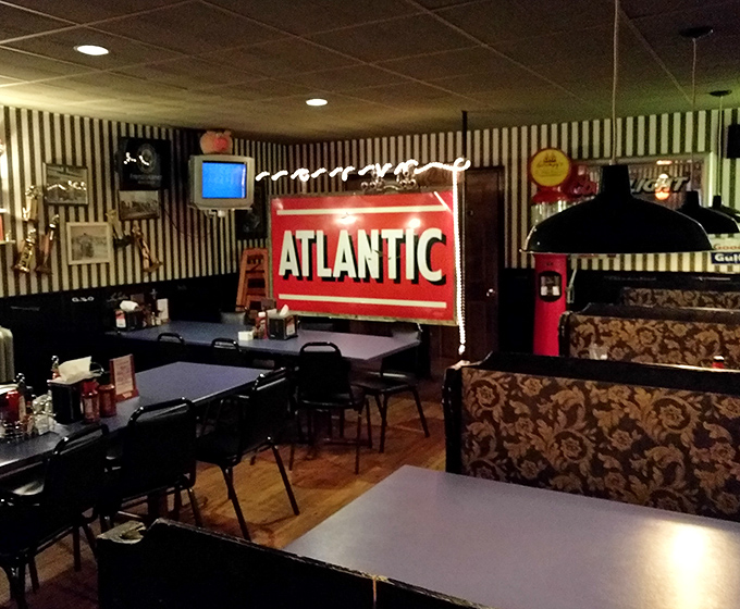 Black and white striped wallpaper meets vintage Americana inside Grumpy's. That glowing Atlantic sign isn't just decoration&mdash;it's a promise of roadhouse authenticity.