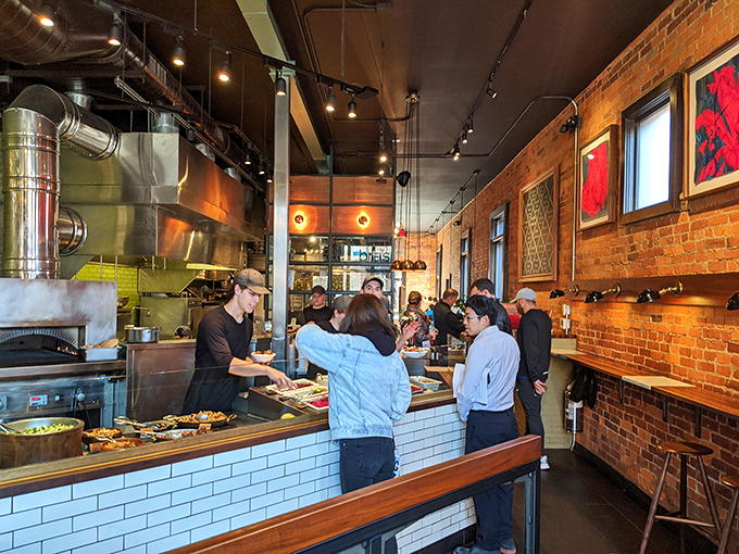 Inside, exposed brick meets industrial chic where culinary theater unfolds. The assembly line may move quickly, but there's nothing rushed about the food.
