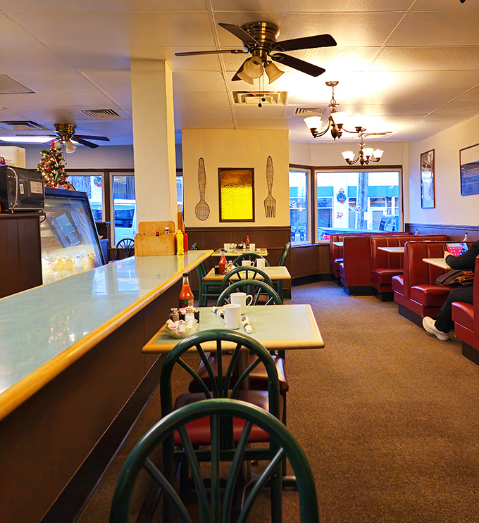 Classic diner aesthetics with those unmistakable green-backed chairs and red booths – like stepping into a Norman Rockwell painting.