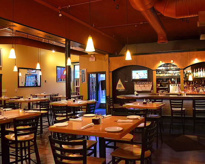 Warm amber lighting transforms simple tables into intimate dining spots. The exposed ductwork and pendant lights create that perfect "discovered gem" atmosphere every food lover craves.