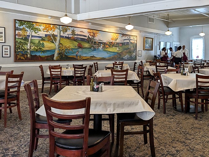 White tablecloths and wooden chairs frame a stunning mural of Southern landscapes—dining room elegance without a hint of pretension.