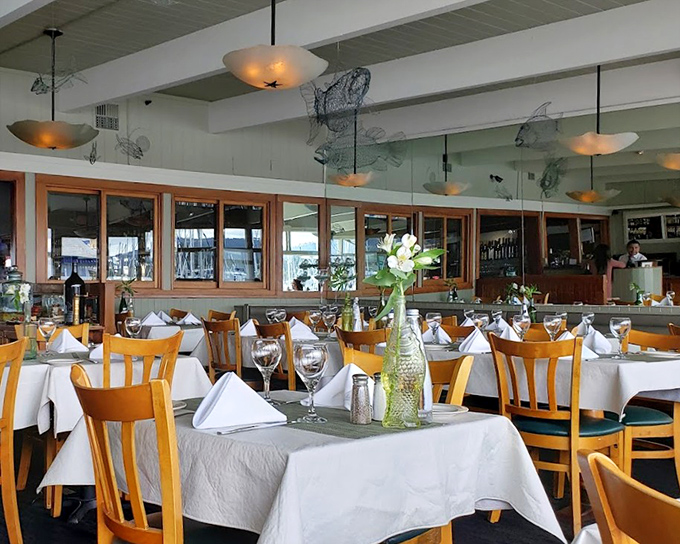 White tablecloths meet honey-colored chairs beneath fishing net decor &ndash; oceanside elegance without pretension, where the view competes with what's on your plate.