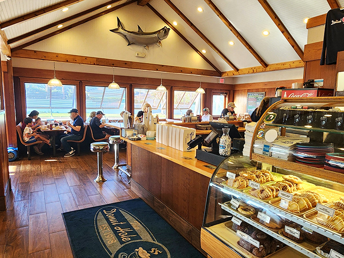 Rustic wooden beams frame this coastal comfort zone where a mounted fish keeps watch over hungry patrons. Breakfast diplomacy happens at these tables daily.