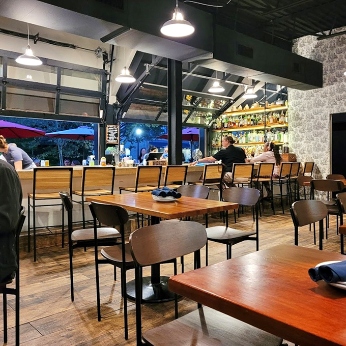 Inside, industrial-chic meets cozy comfort with wooden tables, garage-door windows, and a well-stocked bar that promises good times and better libations.