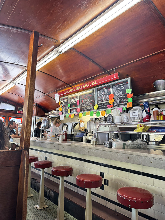 Inside, the warm wooden ceiling hovers above cherry-red counter stools where regulars perch, watching short-order magic happen amid colorful handwritten specials.