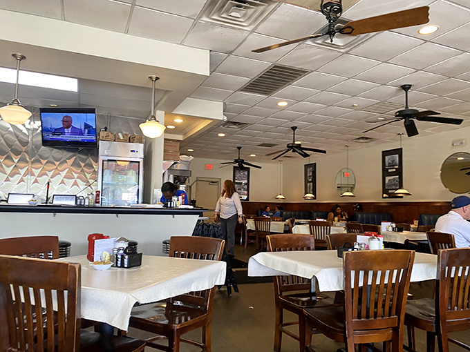 Classic diner ambiance with ceiling fans, wooden chairs, and tables dressed in white - comfort before your meal even arrives.